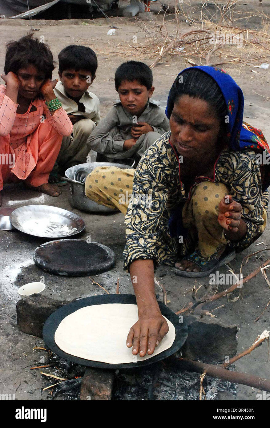 Flood affected woman prepares breads for her children with the help of ...
