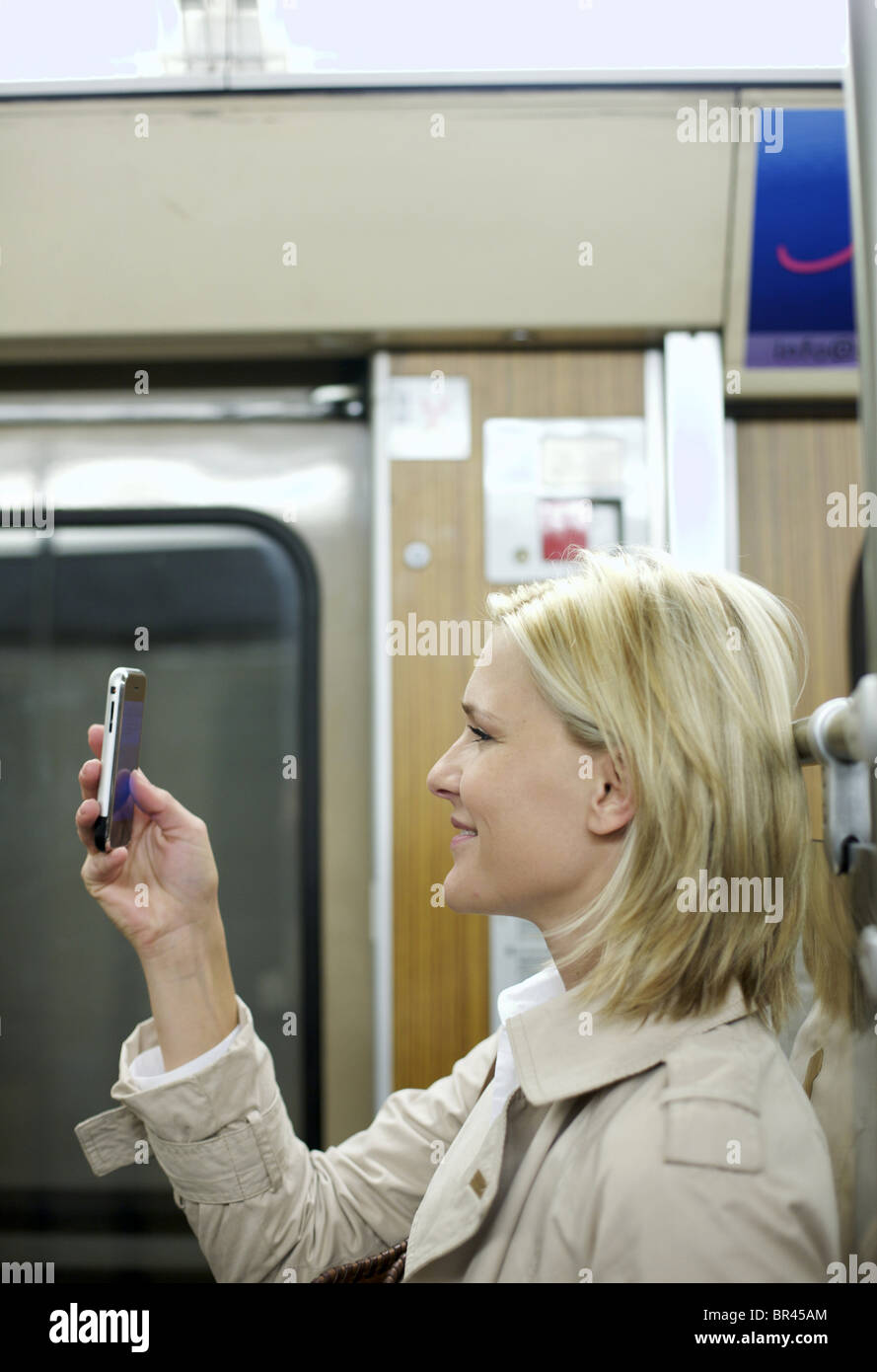 Woman using cell phone in the subway, profile Stock Photo - Alamy