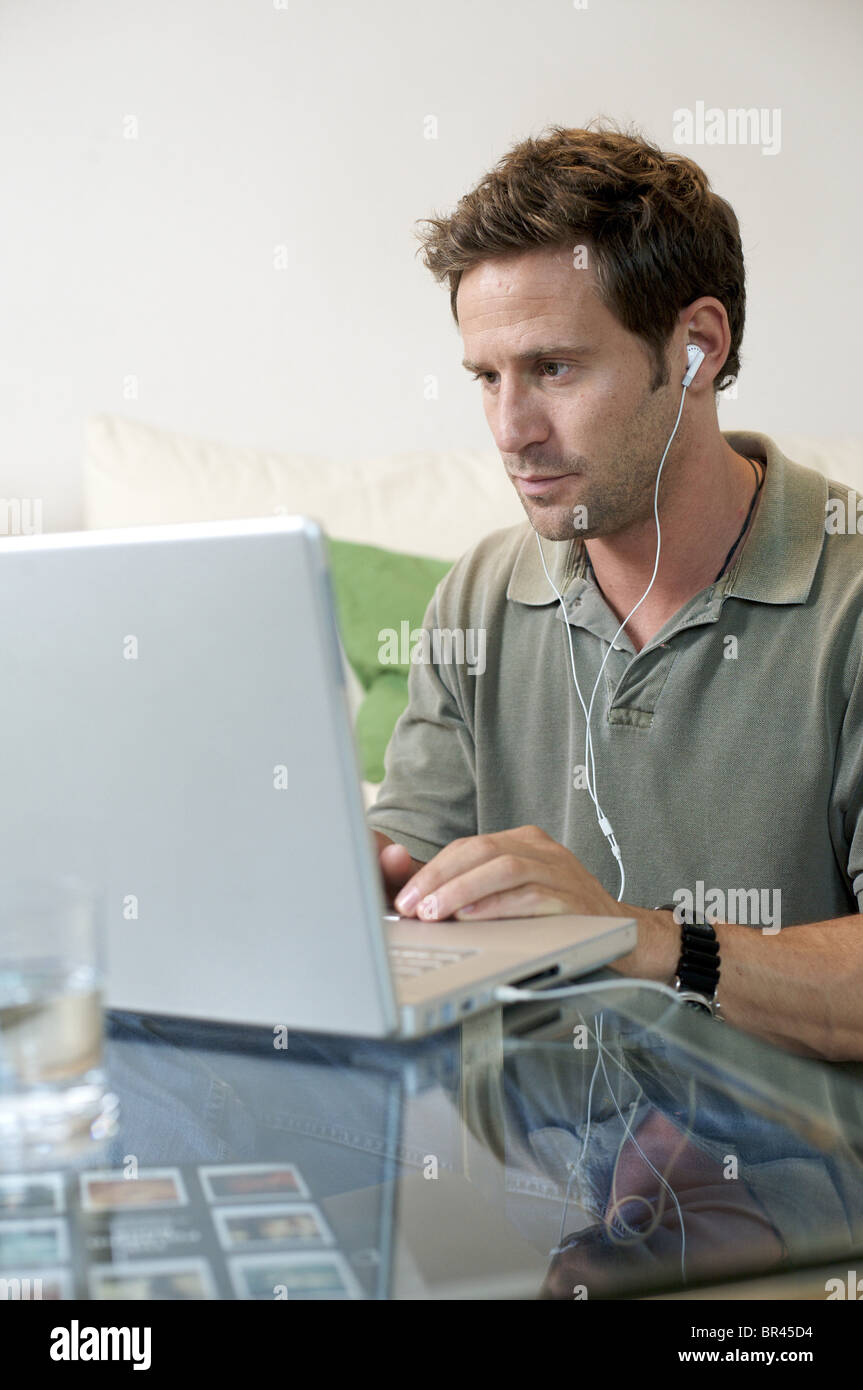 Man with earbuds using laptop Stock Photo - Alamy