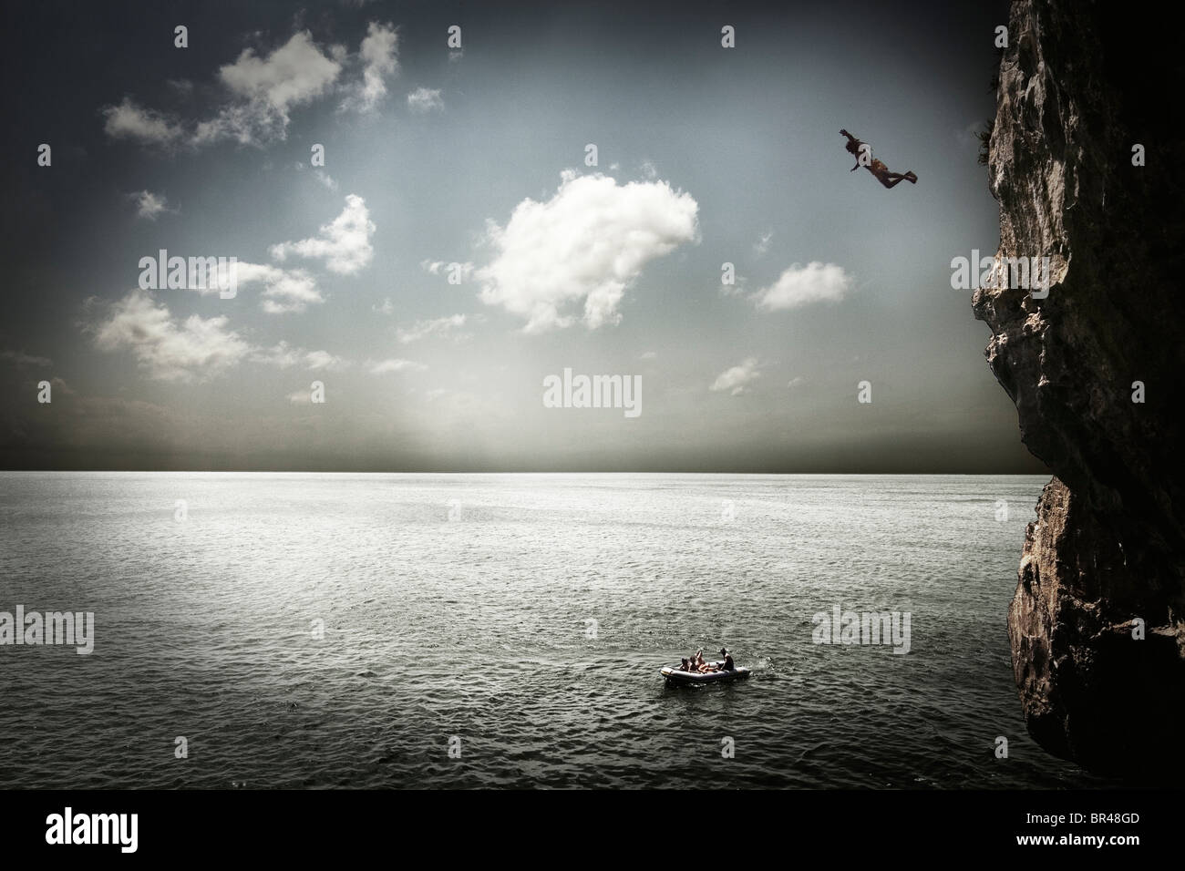 A young man jumps off a sea cliff into the water after free-climbing it ...