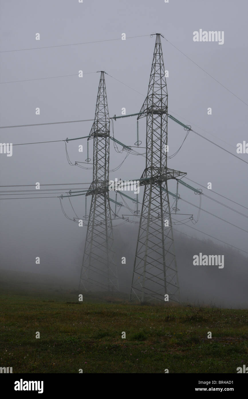 Steel lattice transmission towers and power line in the evening mist ...