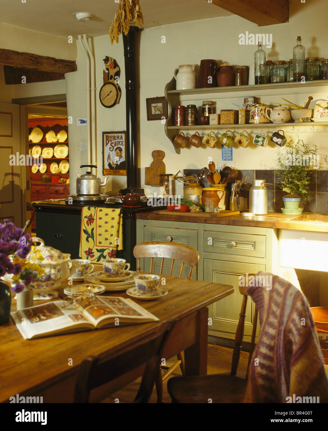 Tea-cups and cookery book on pine table in traditional cottage country ...