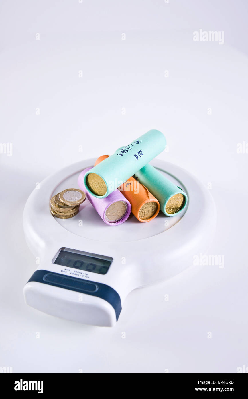 Coin rolls on a weighing scale Stock Photo - Alamy