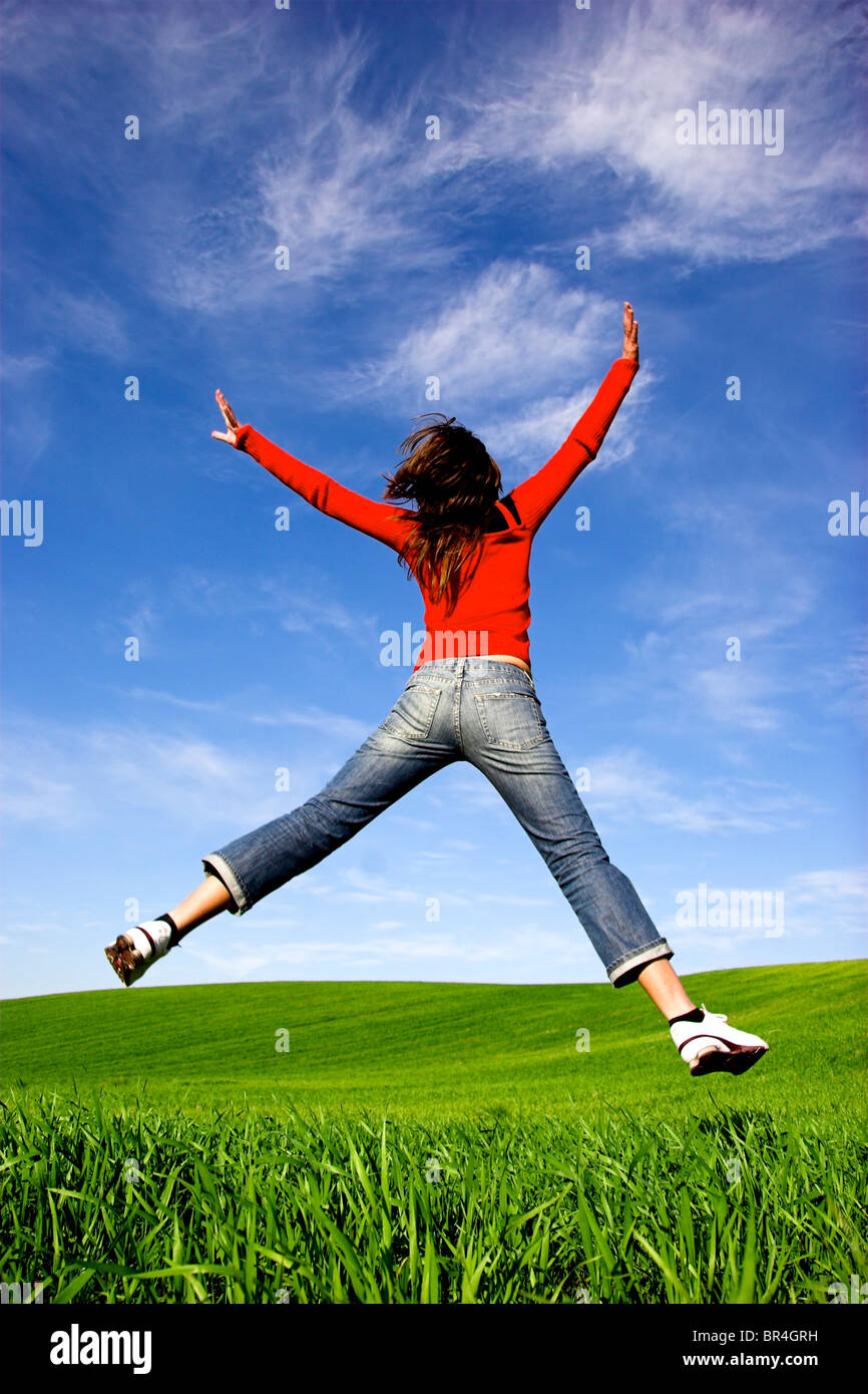 Woman making a big jump on a beautiful green meadow Stock Photo - Alamy