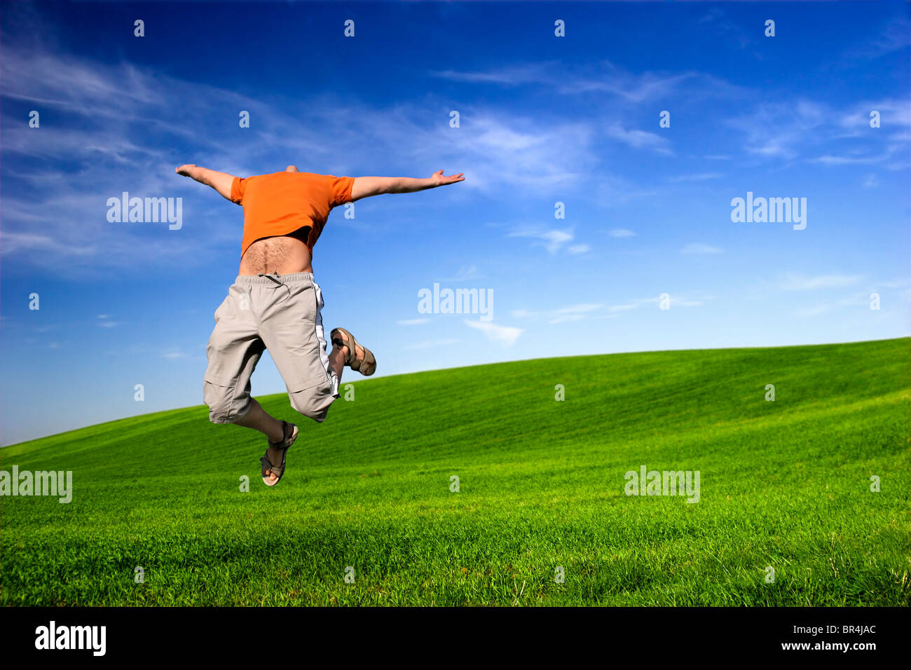 Man making a big jump on a beautiful green meadow Stock Photo - Alamy