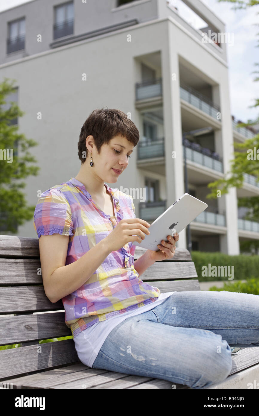 Young woman using iPad on a bench Stock Photo - Alamy