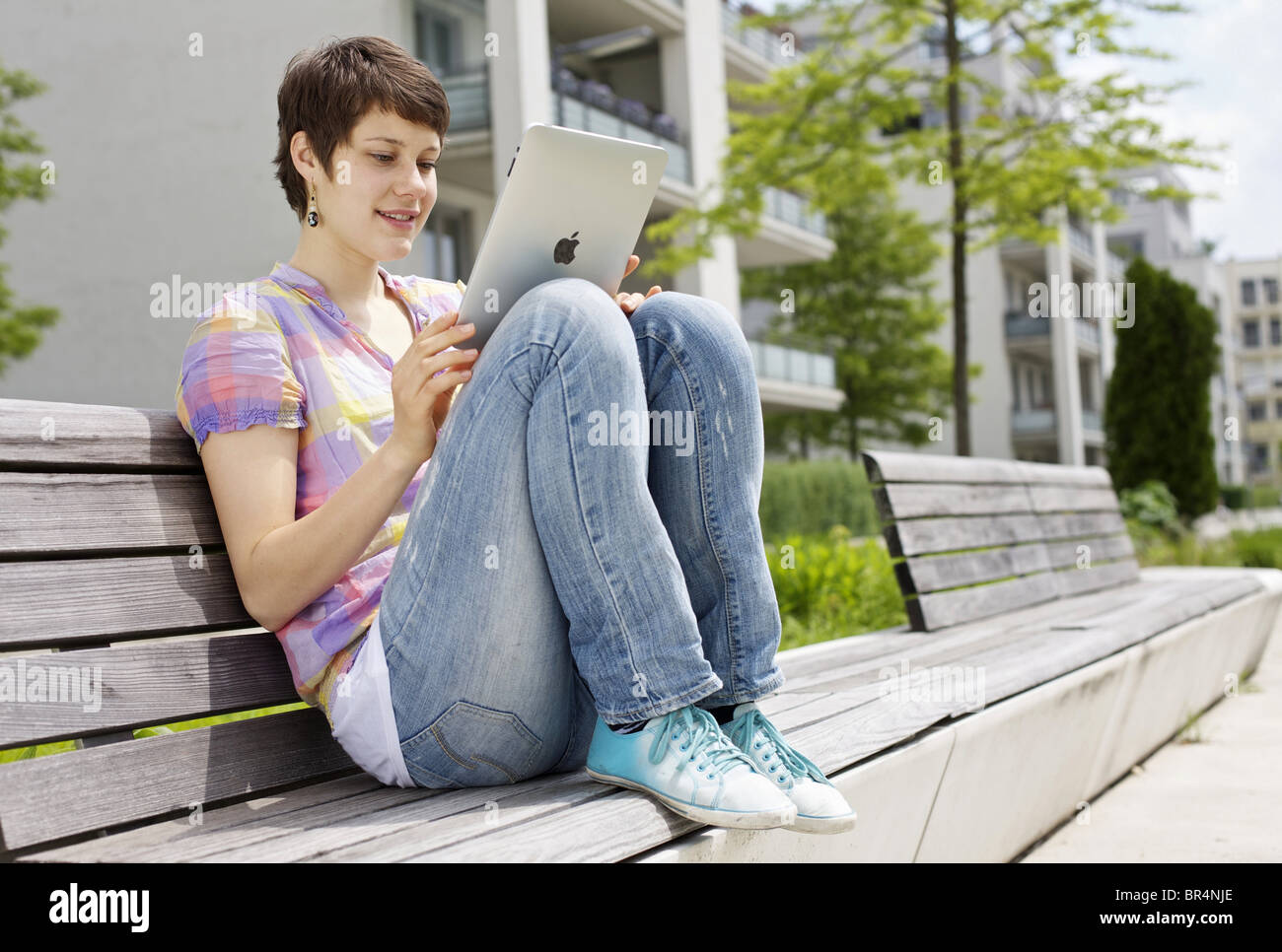Young woman using iPad on a bench Stock Photo - Alamy