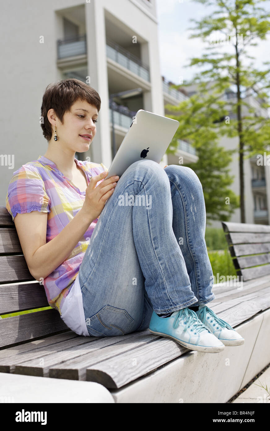Young woman using iPad on a bench Stock Photo - Alamy