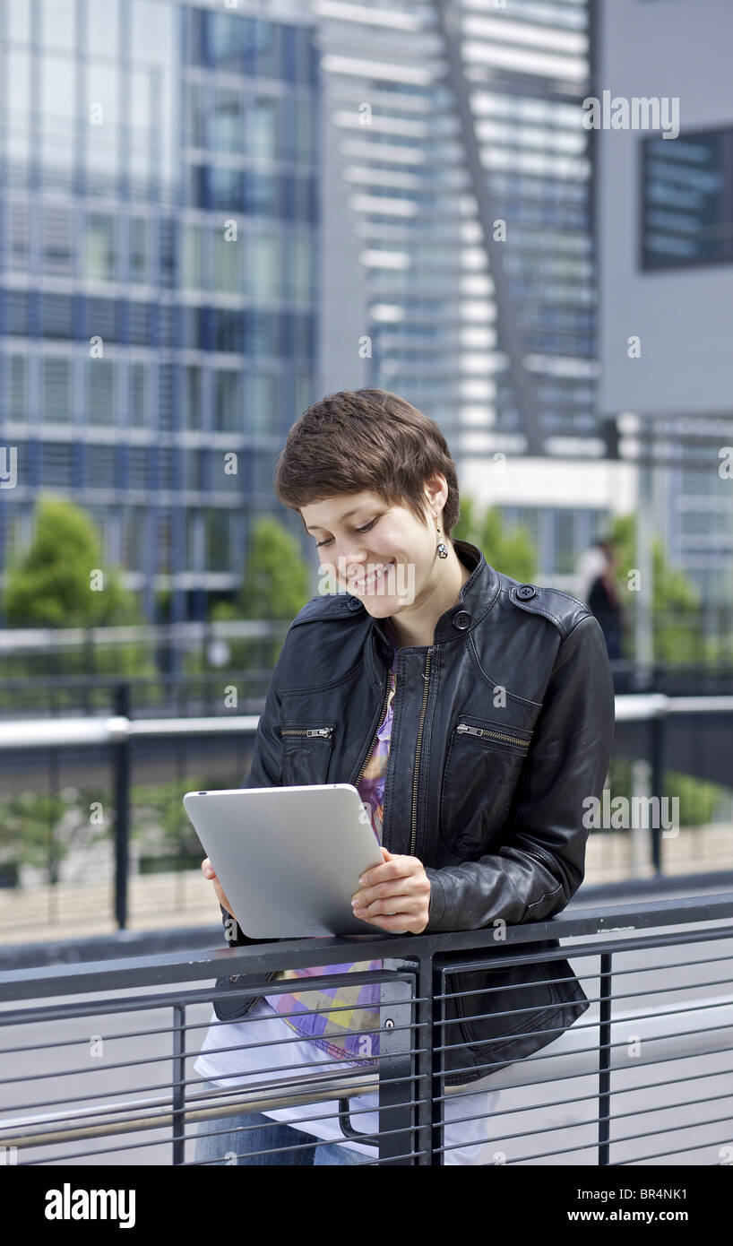 Young woman using iPad in front of an office building Stock Photo - Alamy