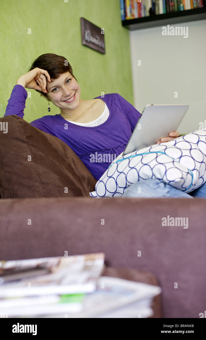 Young woman using iPad on couch Stock Photo - Alamy