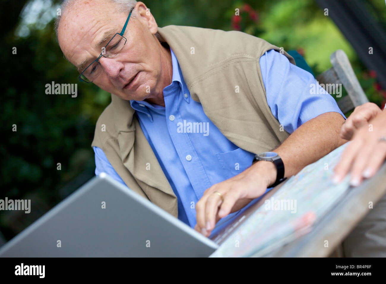 Senior man laptop and road map, close-up Stock Photo - Alamy