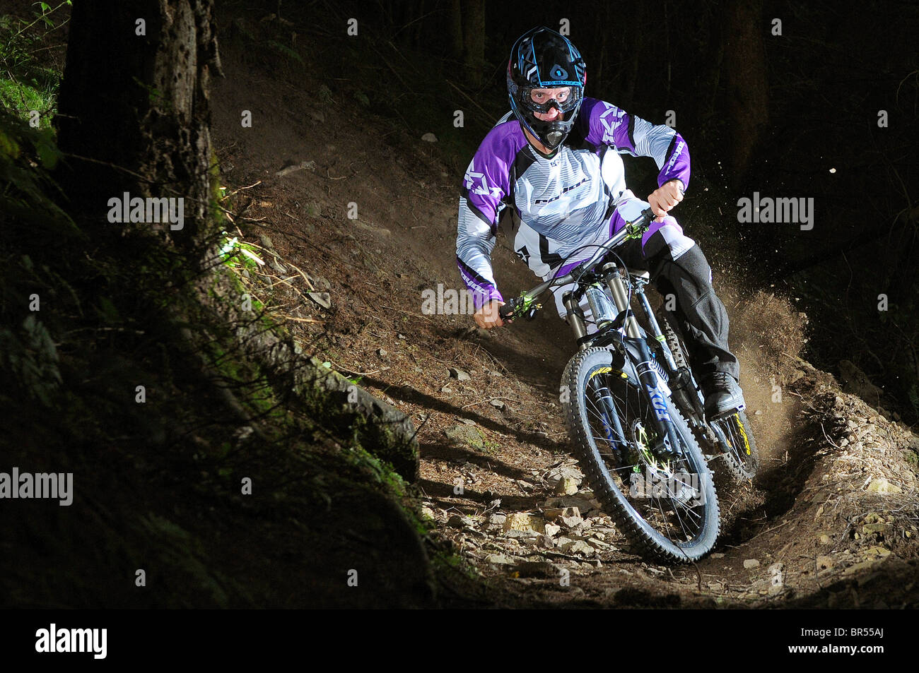 A downhill mountain biker corners at speed on a trail in woodland Stock ...