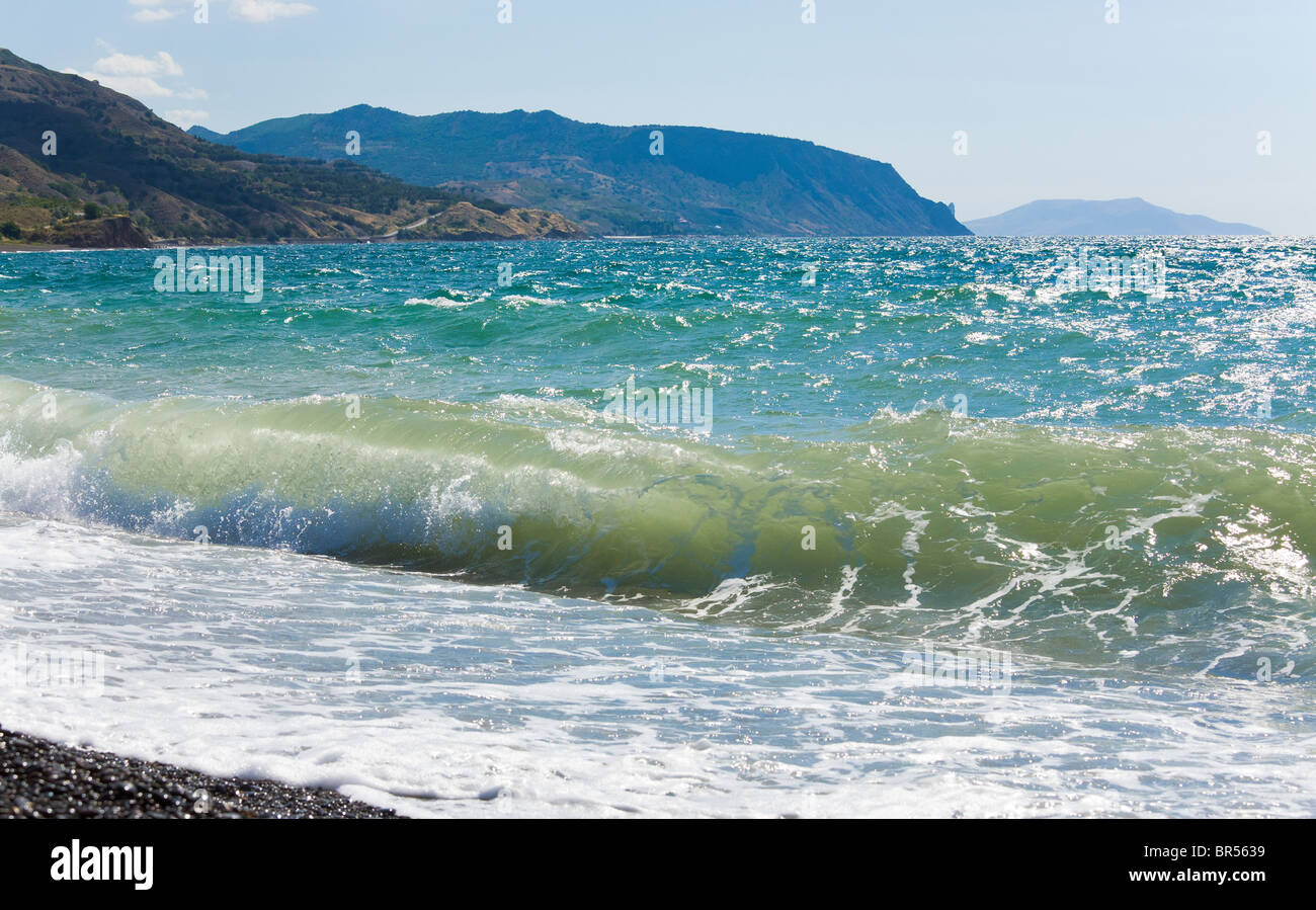 Sea surf wave break on coastline and Meganom cape on horizon right ...