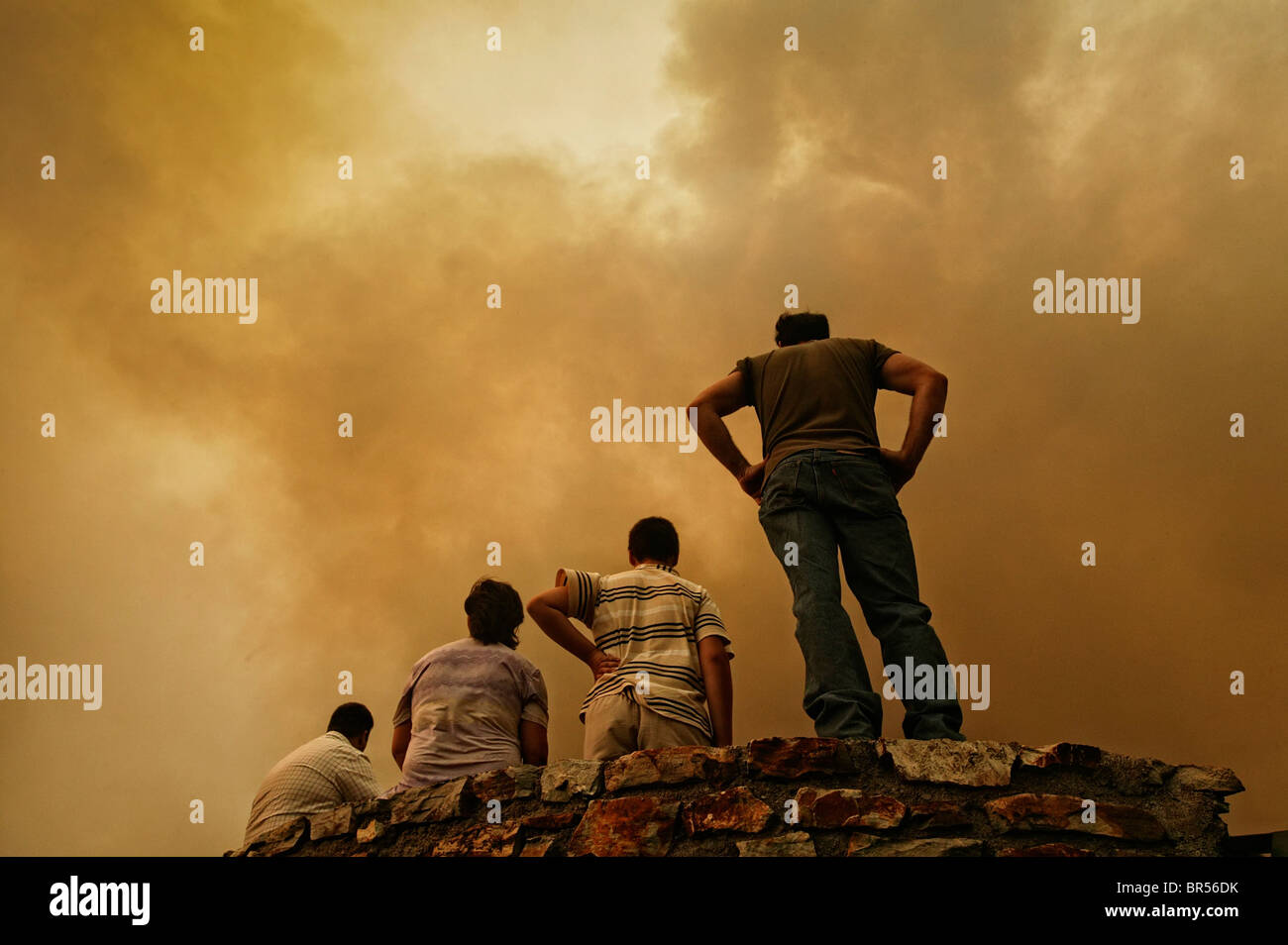 Helpless people look on as a rampant wildfire threatens their homes ...