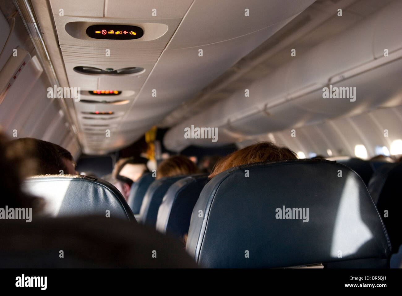 Airplane interior with rows of seated airline passengers Stock Photo ...