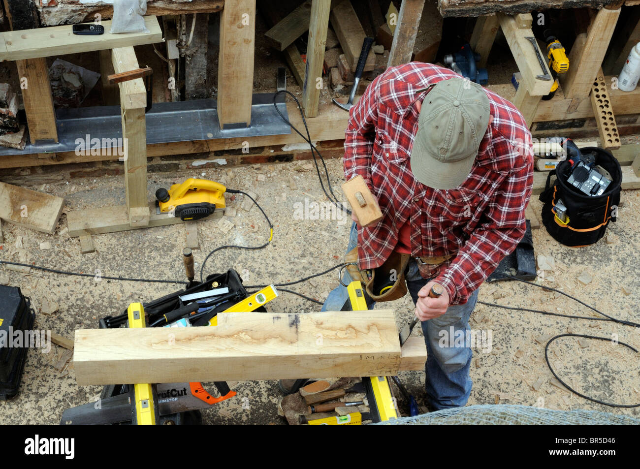 Renovating an old timber framed building carpenter using a chisel to ...