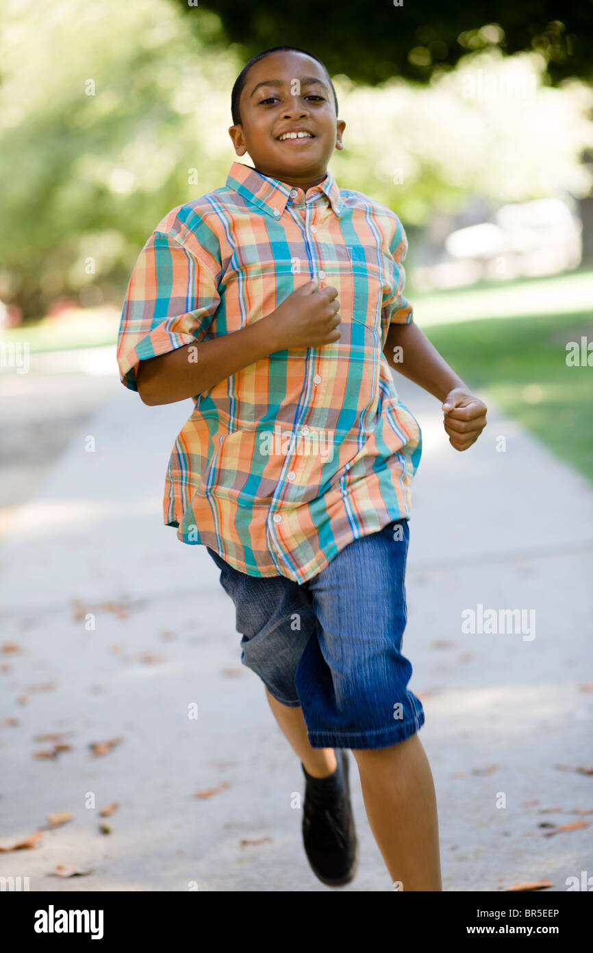 Mixed race boy running on sidewalk Stock Photo - Alamy
