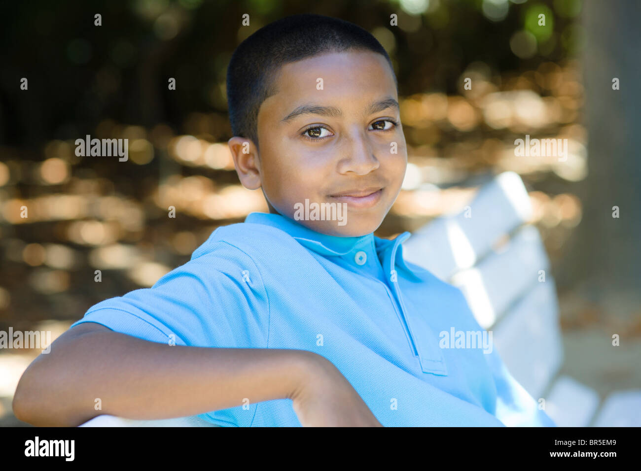 Smiling mixed race boy sitting in park Stock Photo - Alamy