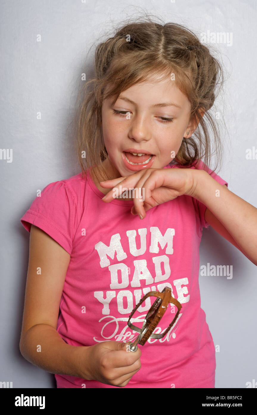 Young girl eating chocolate icing off a whisk Stock Photo - Alamy