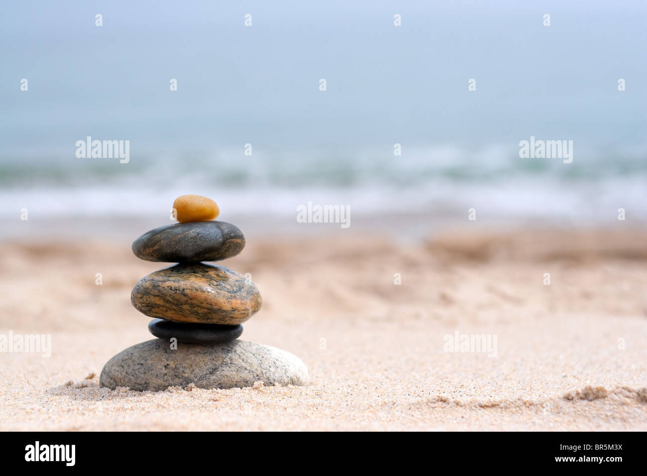 A pile of round smooth zen rocks stacked in the sand at the beach Stock ...