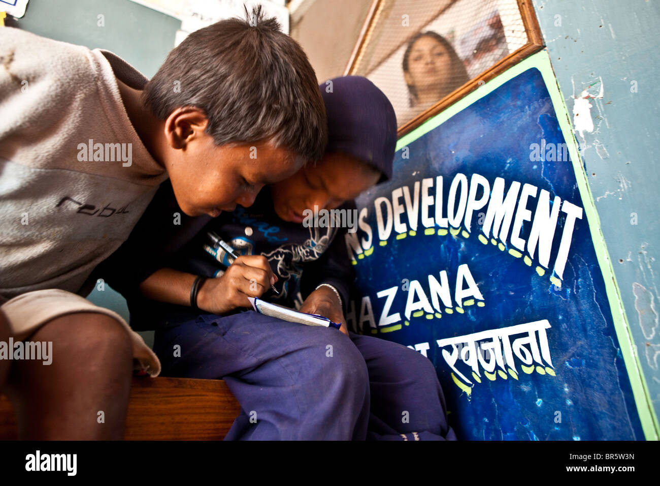 Two boys pay money they have earned collecting scrap into the children ...