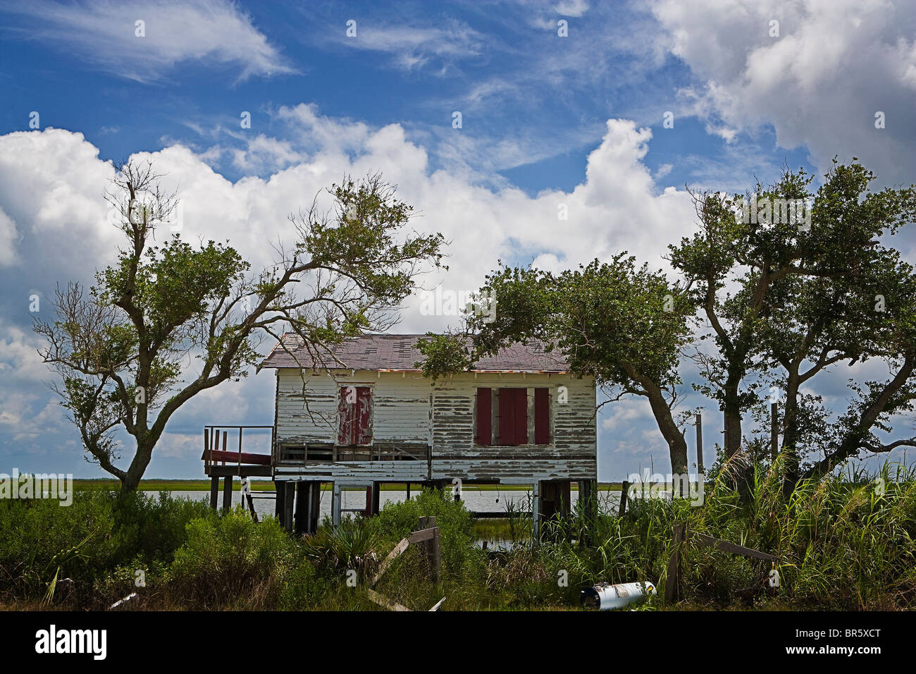 An old and abandoned building on stilts sits at the water's edge along ...