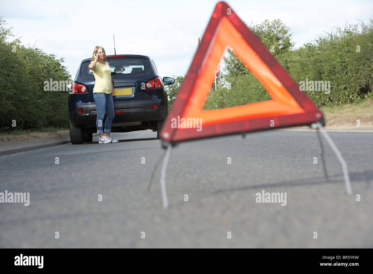 Female Driver Broken Down On Country Road With Hazard Warning Sign In ...