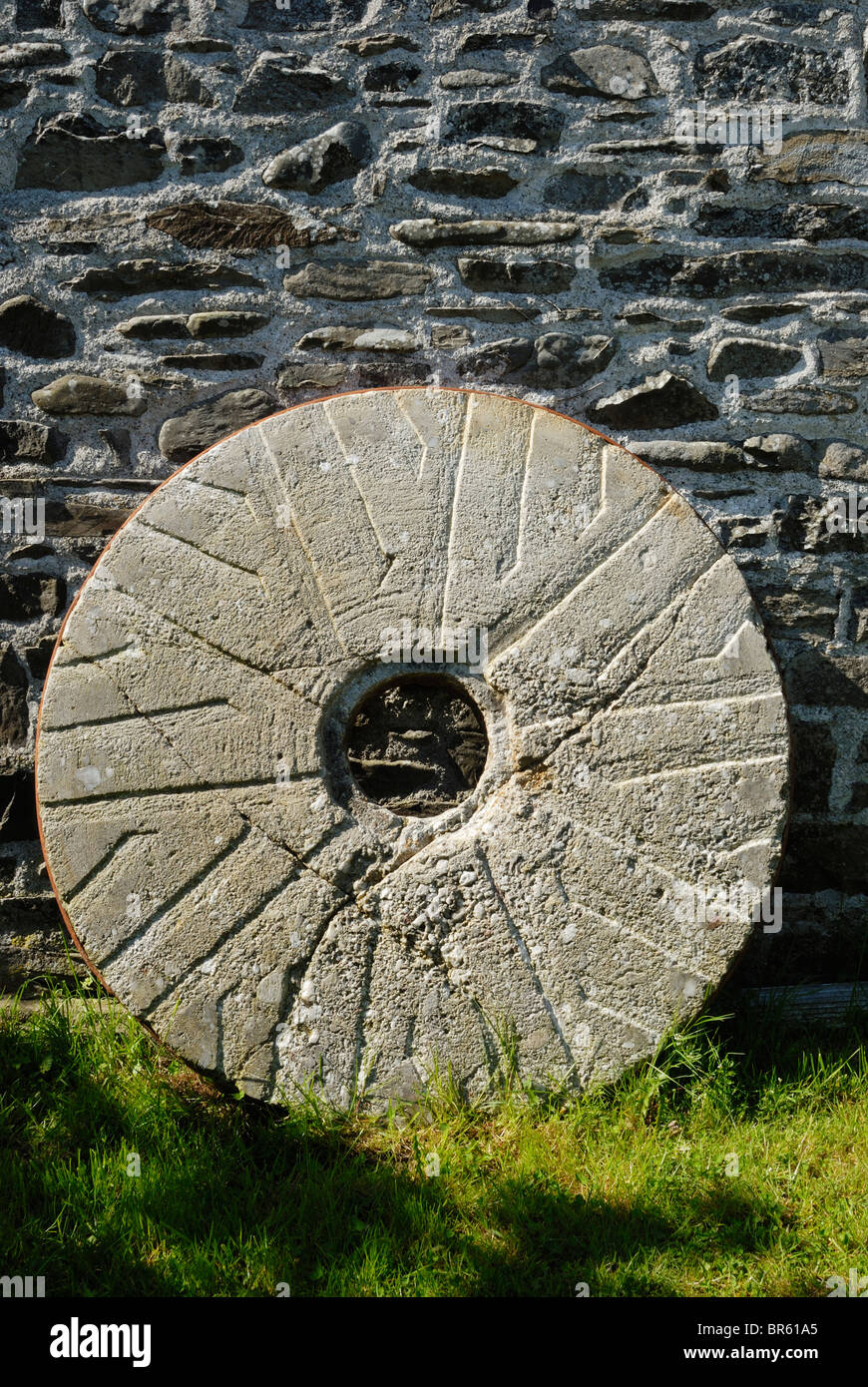 Old millstone leaning against a building, Wales Stock Photo - Alamy