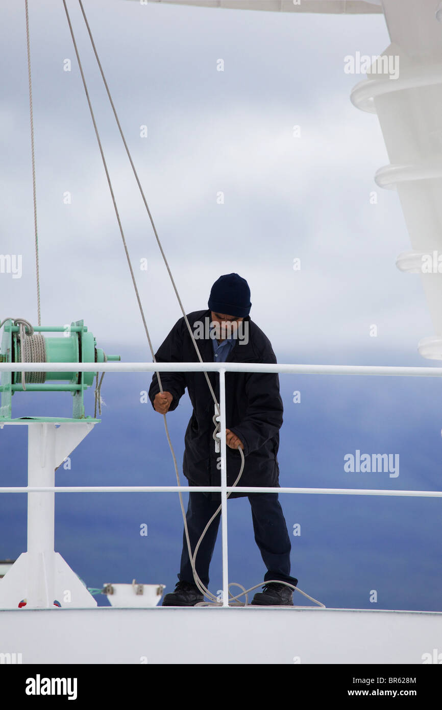 A ship worker hoisting the Icelandic flag as the cruise ship approaches ...