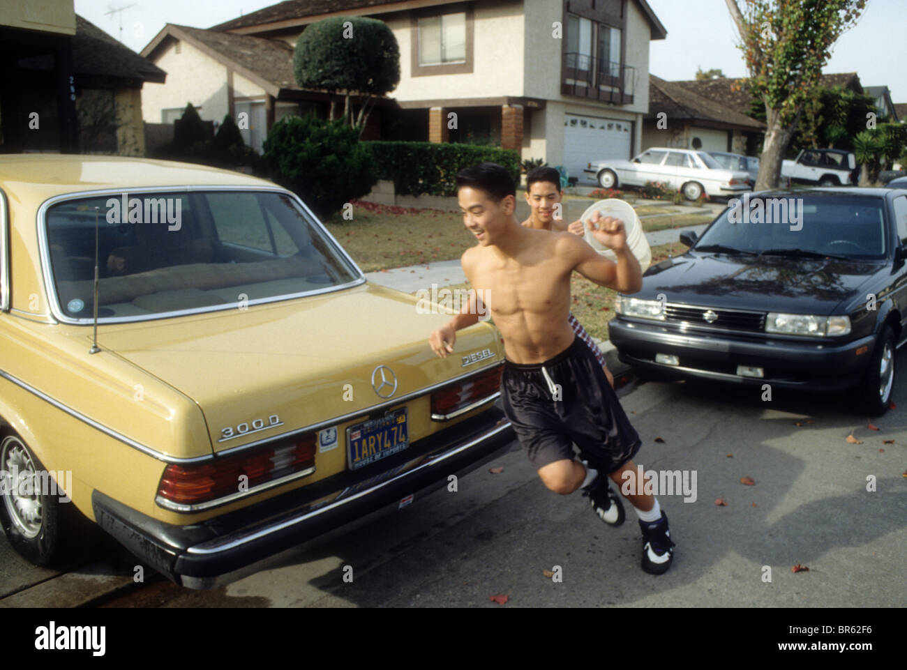 Twin Asian Vietnamese-American brother chase each other while washing ...
