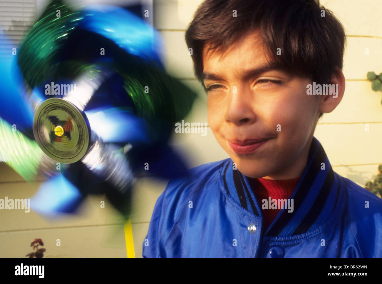Hispanic boy blow pinwheel toy spin energy action fast blade propeller ...