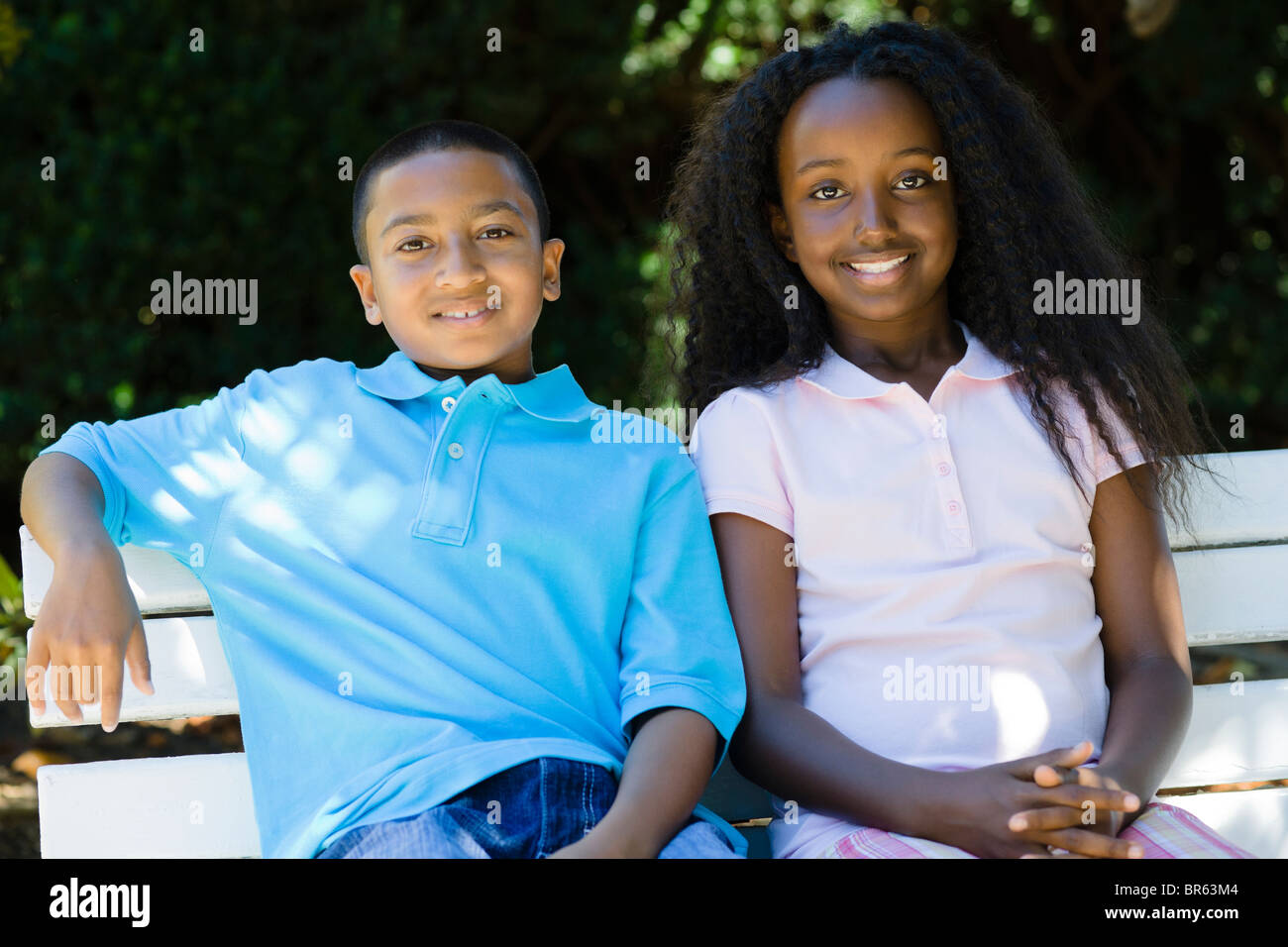 Smiling children sitting on park bench Stock Photo - Alamy