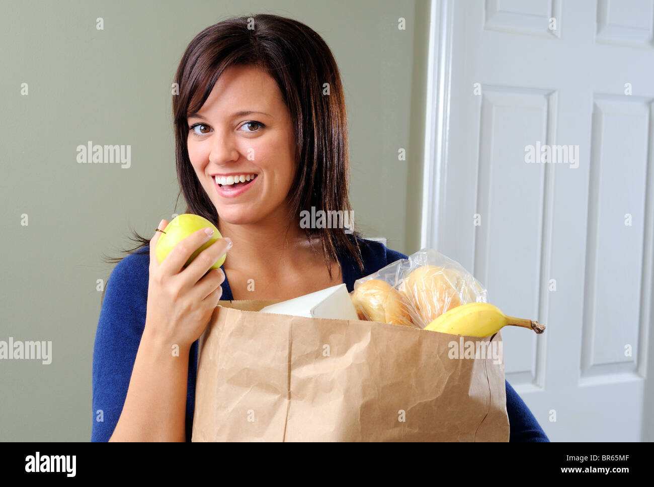 Woman Enjoying A Healthy Snack Returning Home With Groceries Stock ...