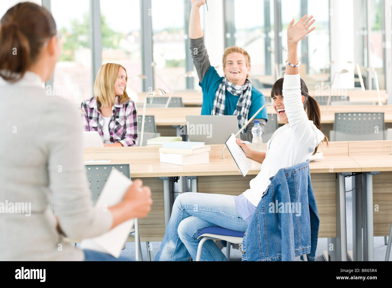 High school students raising hands, in classroom with professor Stock ...