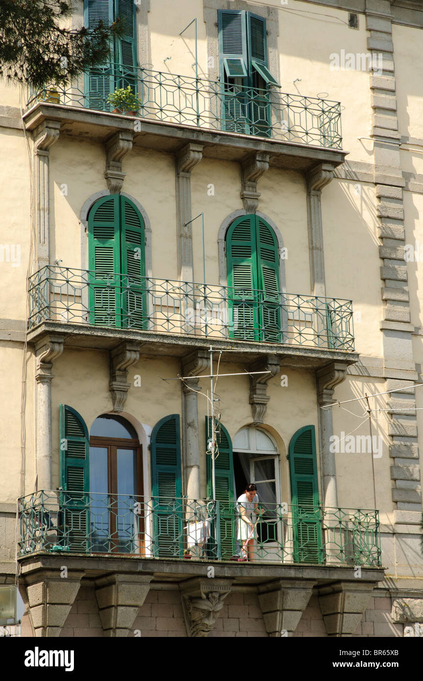 balconies with shuttered doors and woman sweeping Stock Photo - Alamy