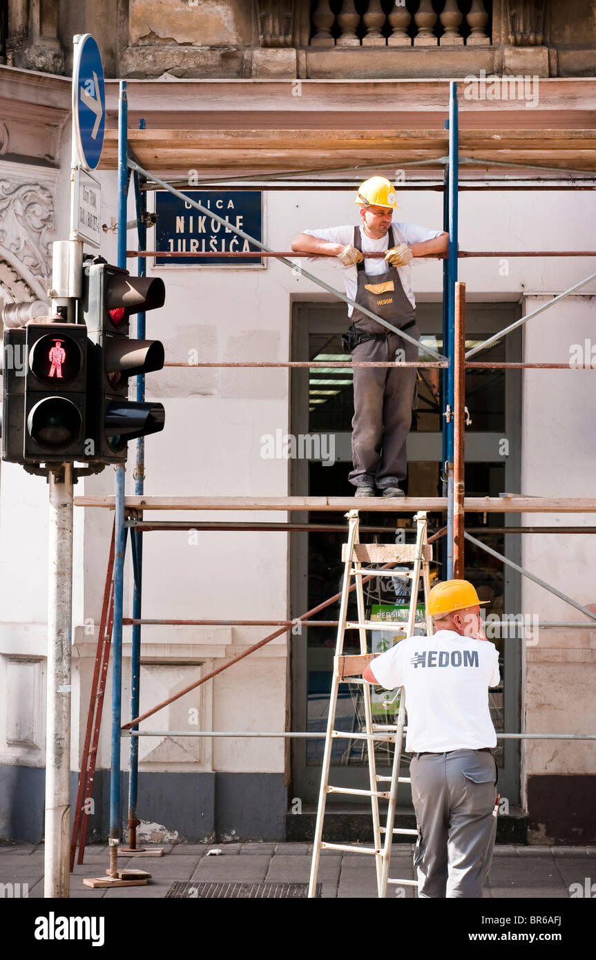 Street workers, doing a renovation of a corner building stand up ...