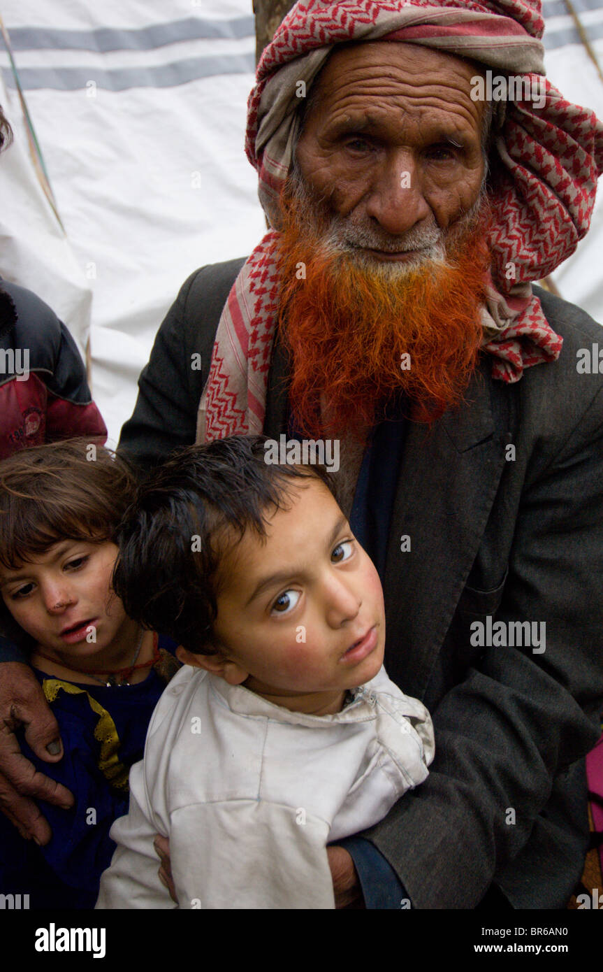 A Pashtun man holds his children in front of a tent erected in the ...