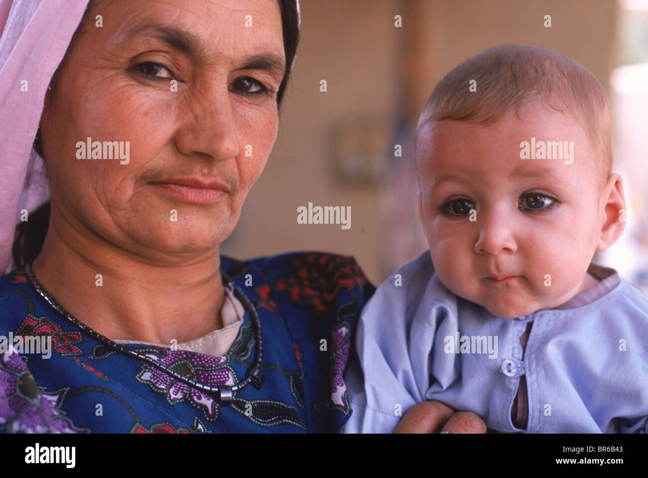 A Tajik woman holds a baby with kohl rimmed eyes in a family home Mazar ...
