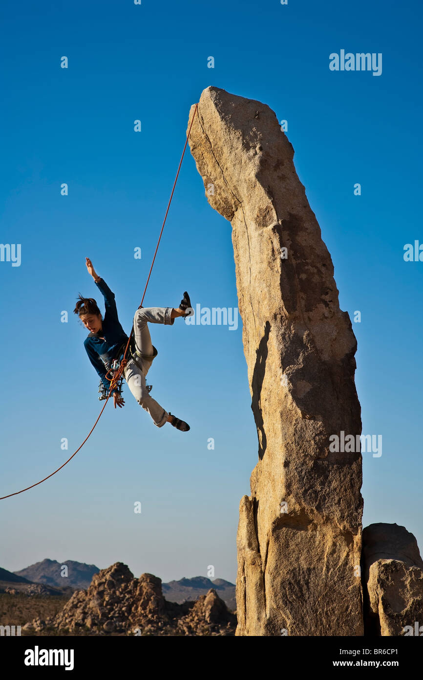 Climber in trouble dangling from her rope as she scales a rock pinnacle ...