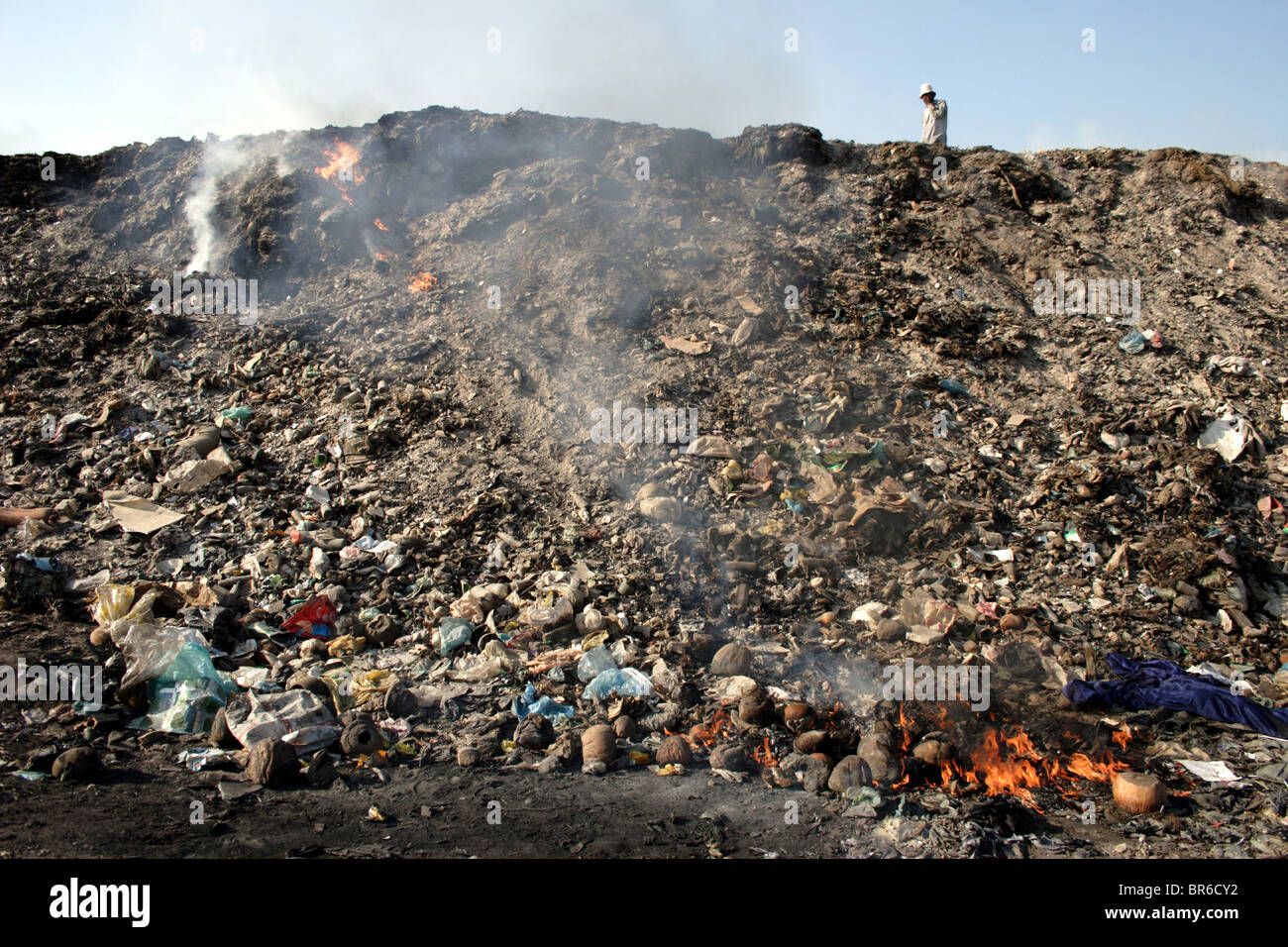 A man walks on top of a huge mound of burning garbage at The Stung ...