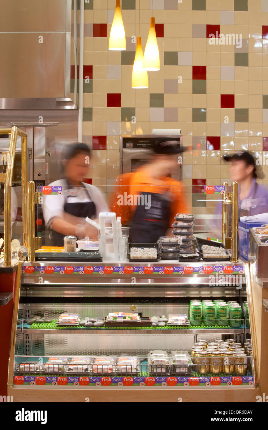 Three employees (blurred) working behind the counter at an eatery in a ...