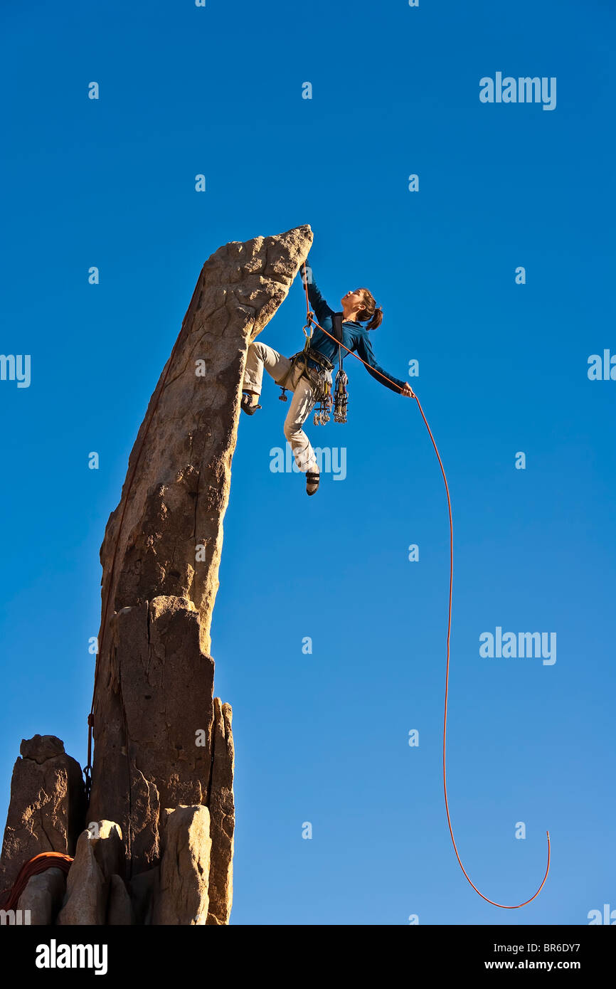 Climber in trouble dangling from her rope as she scales a rock pinnacle ...