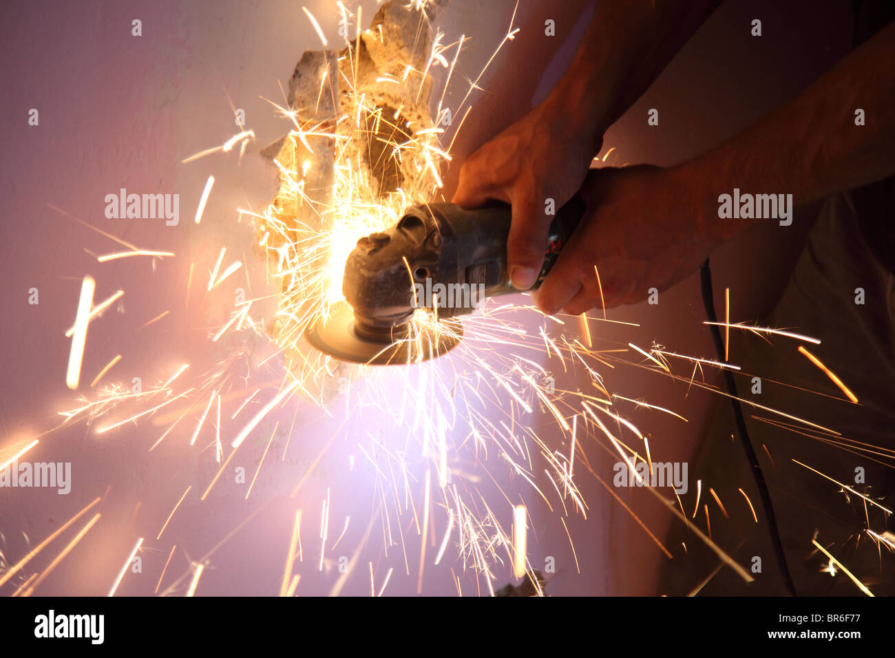 Plumber cuts through metal pipe with radial saw making orange sparks ...