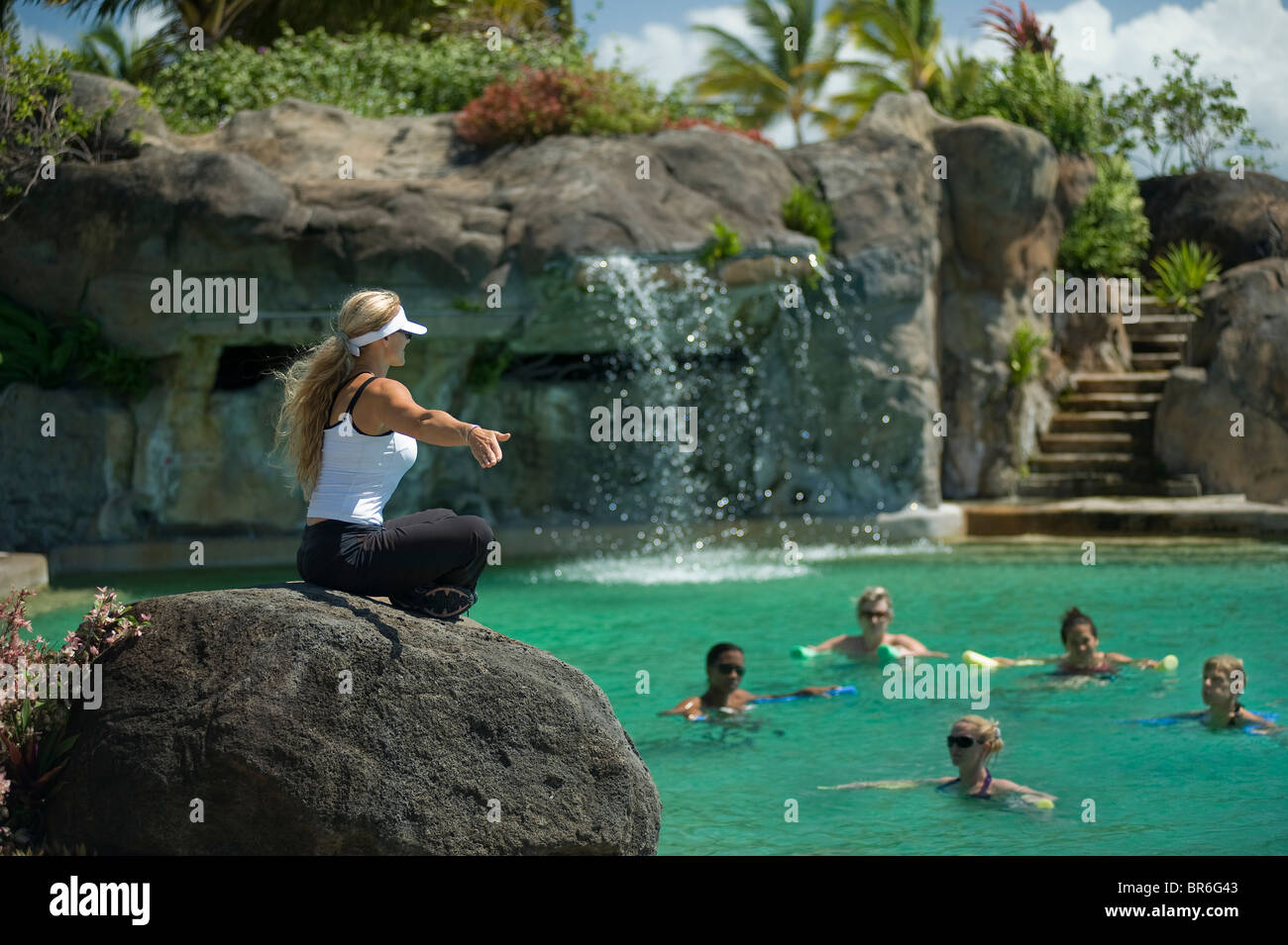 Female trainer coach instructing people in water aerobics class in a ...
