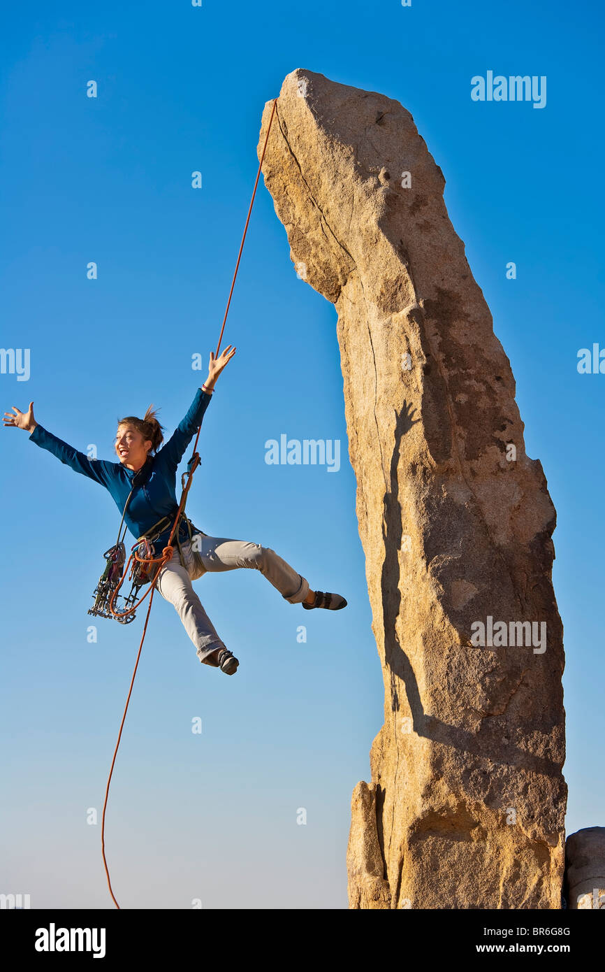 Climber in trouble dangling from her rope as she scales a rock pinnacle ...