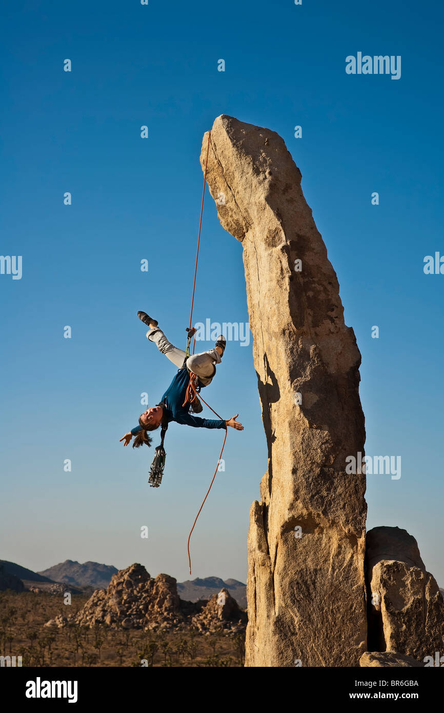 Climber in trouble dangling from her rope as she scales a rock pinnacle ...