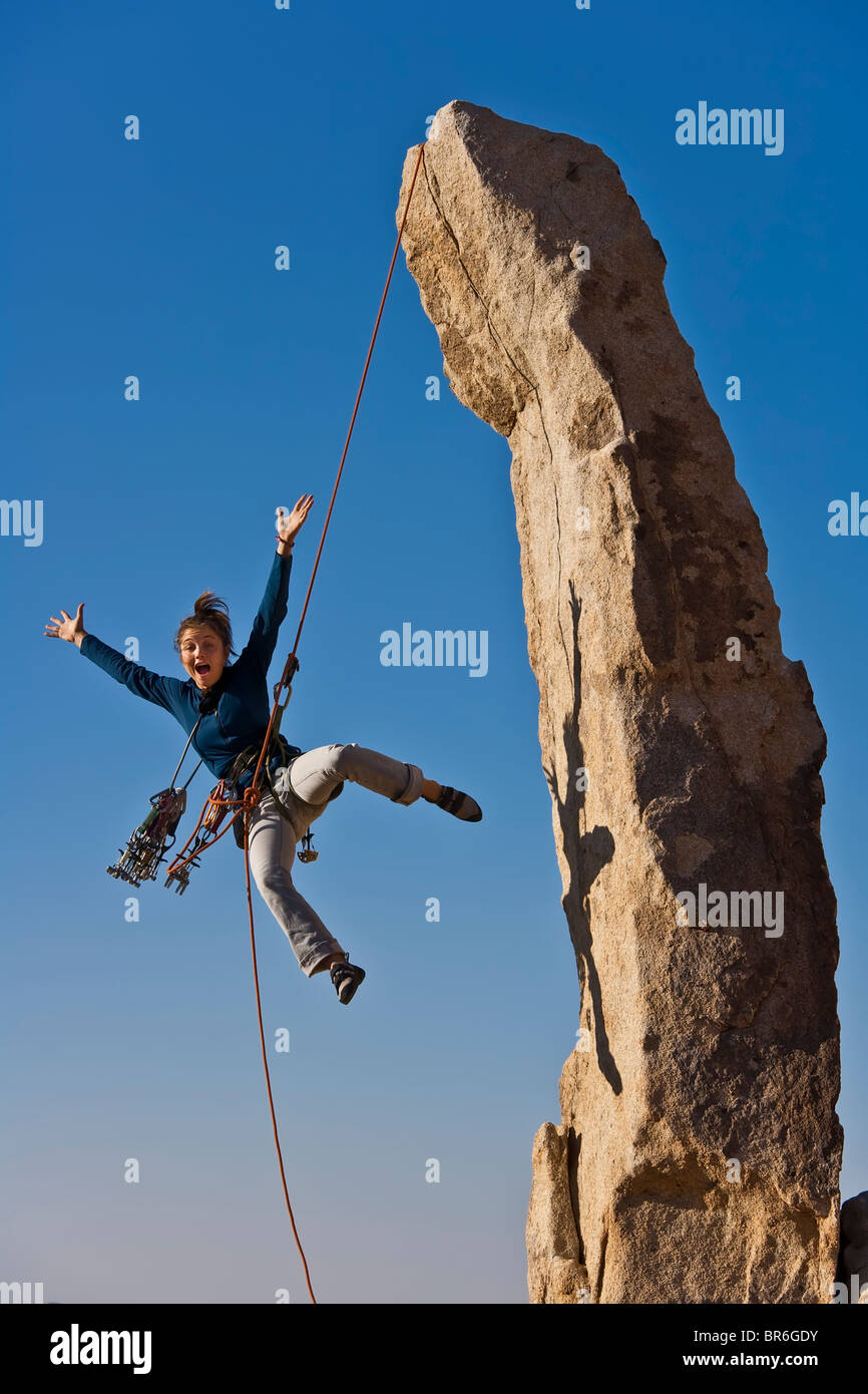Climber in trouble dangling from her rope as she scales a rock pinnacle ...