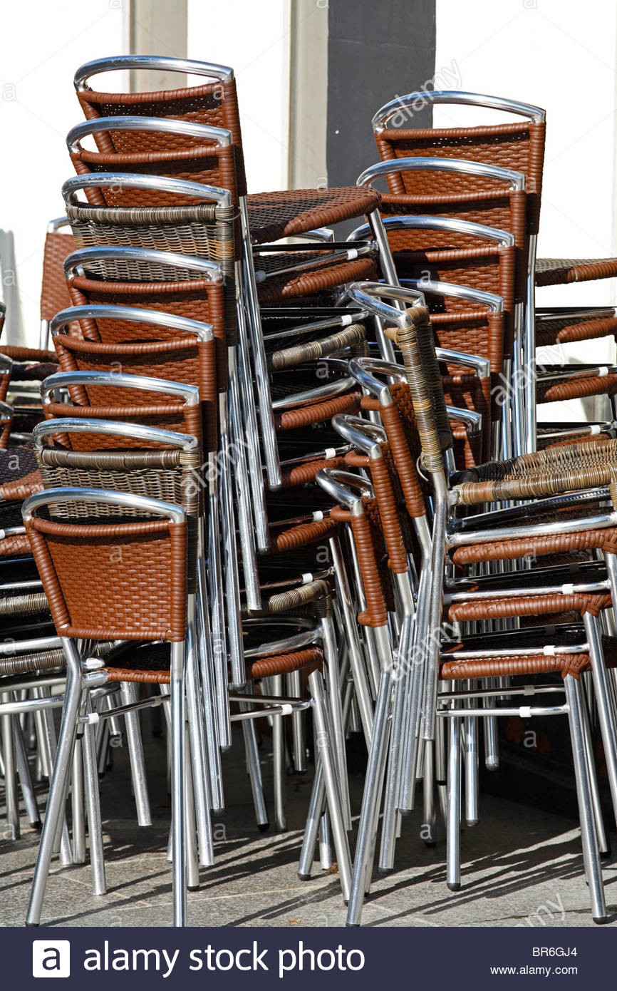 Stacked chairs on pavement outside a cafe Stock Photo - Alamy