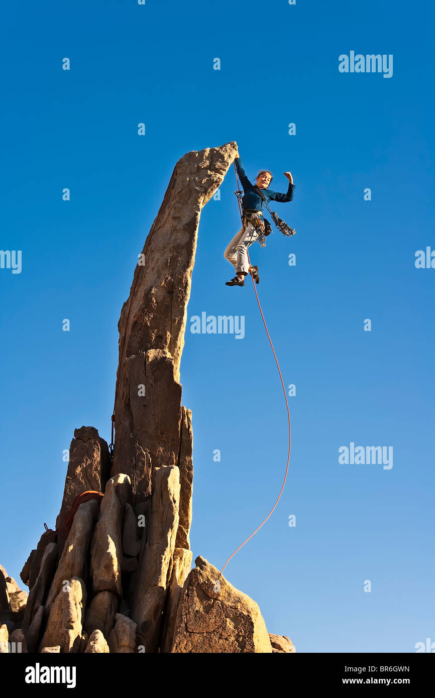 Climber in trouble dangling from her rope as she scales a rock pinnacle ...