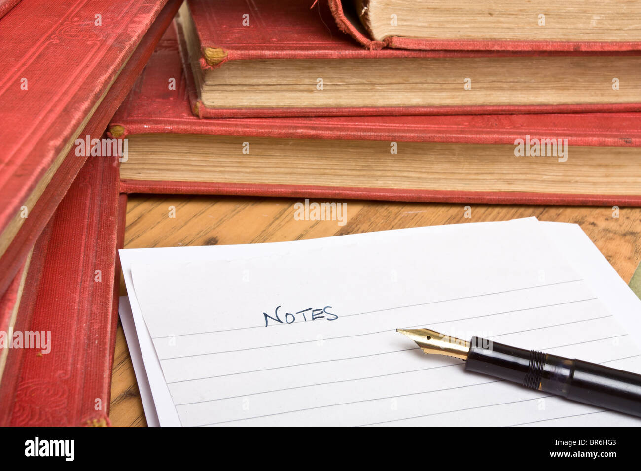 Pile of old books, note paper and fountain pen to depict research ...